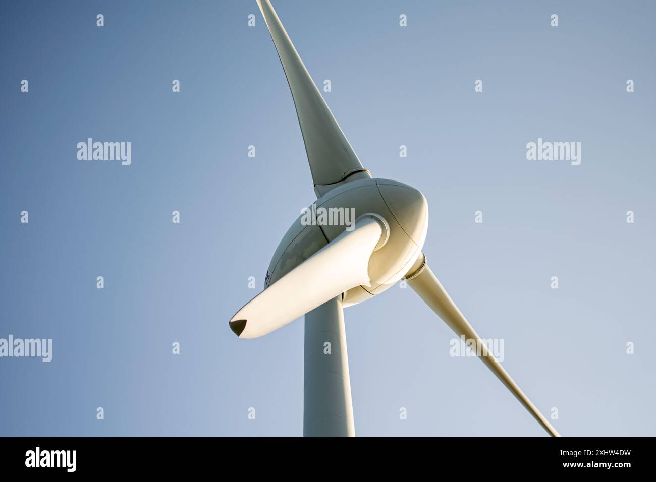 This image captures a close-up, low-angle view of a modern wind turbine ...