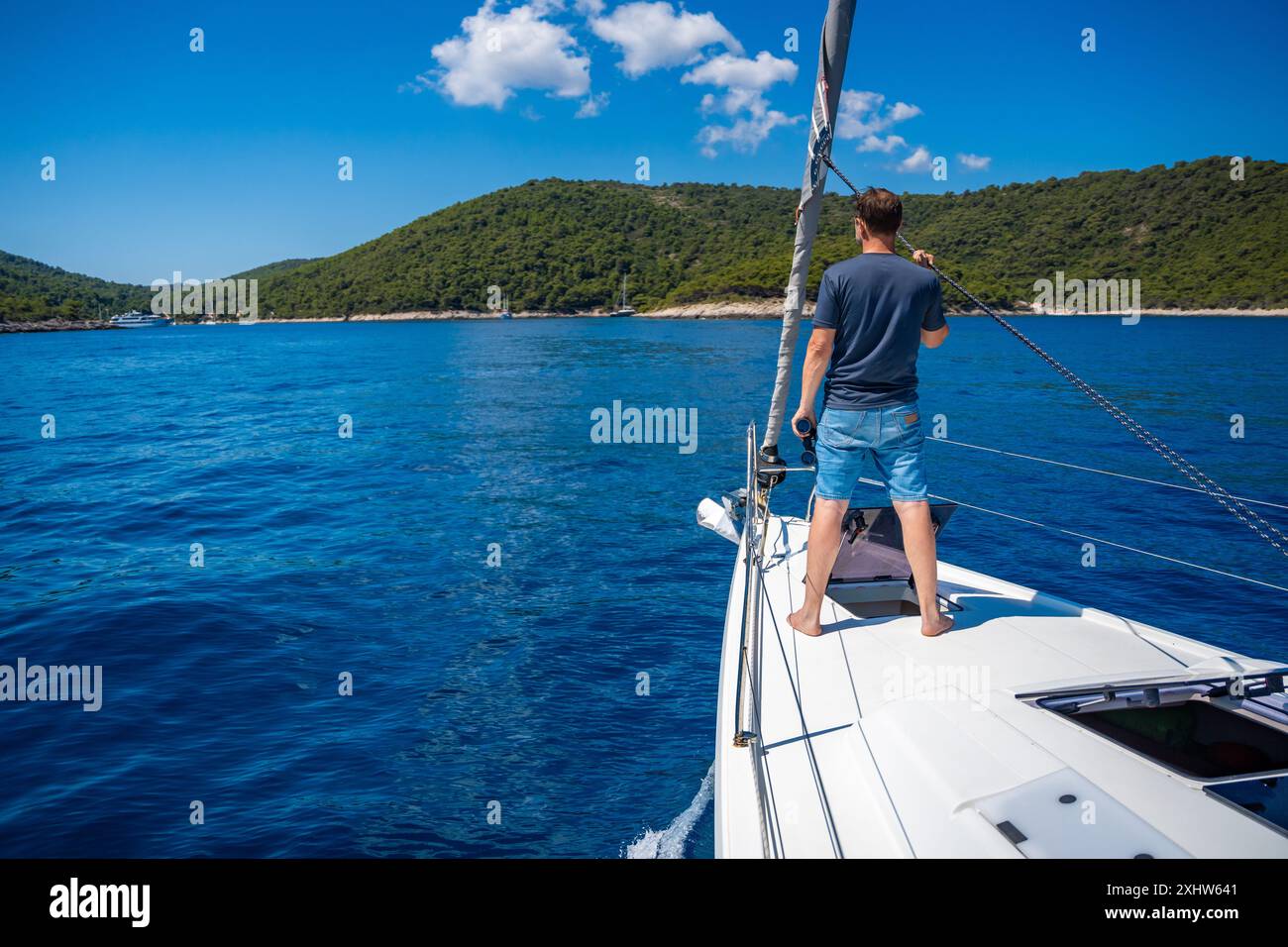 Young man captain on the yacht looking through binoculars during ...