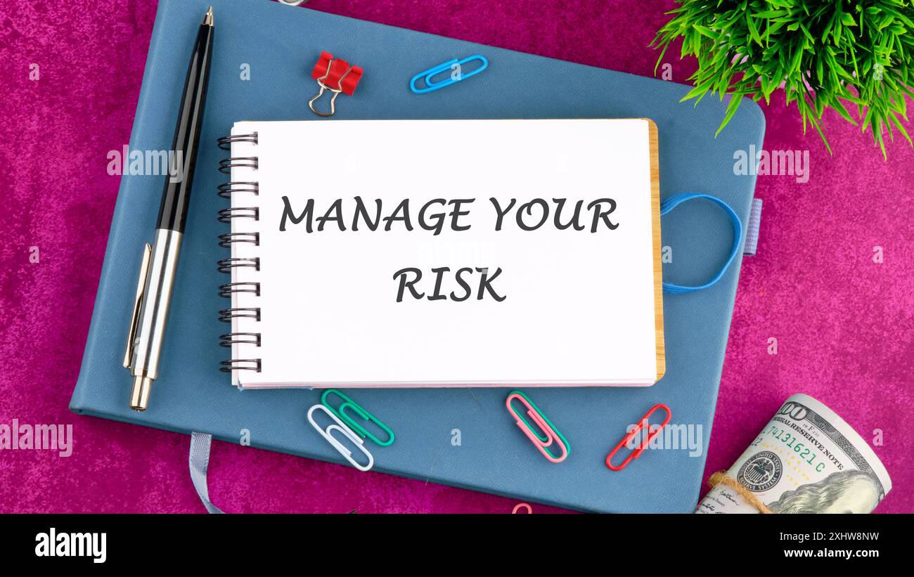 MANAGE YOUR RISK text written in the notebook lying on the business ...