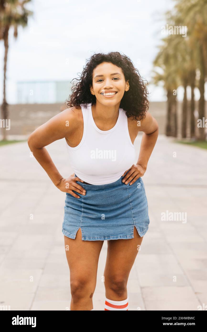 Portrairt of a young smiling woman with her hands on her hips, enjoying ...