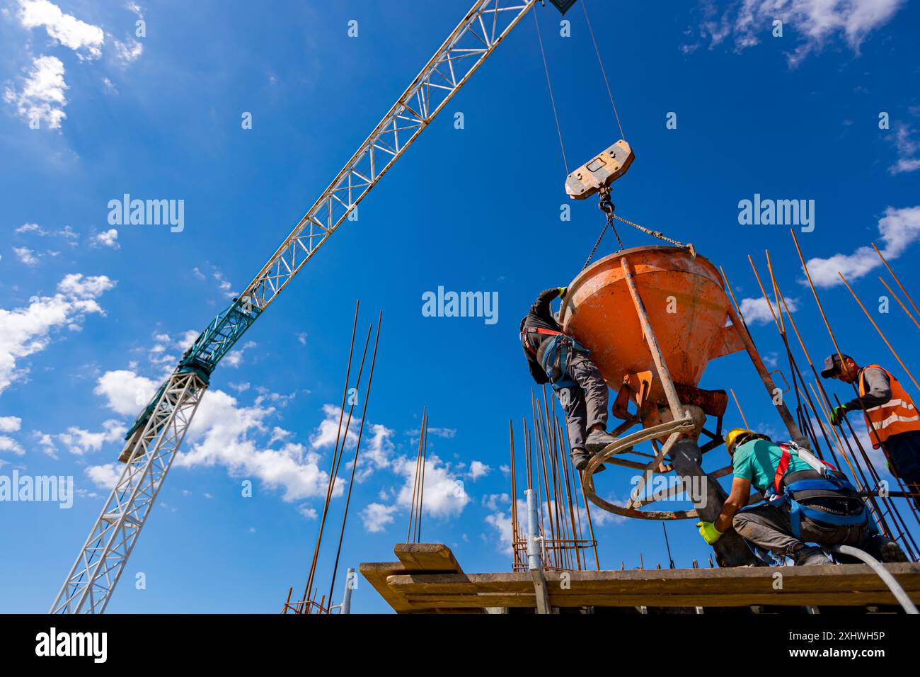 Construction workers are unloading conical metal bucket, transport and ...