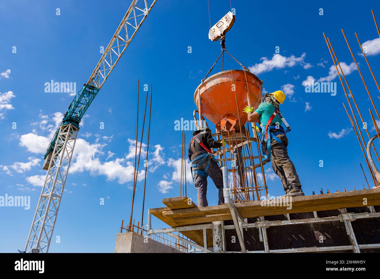 Construction workers are unloading conical metal bucket, transport and ...
