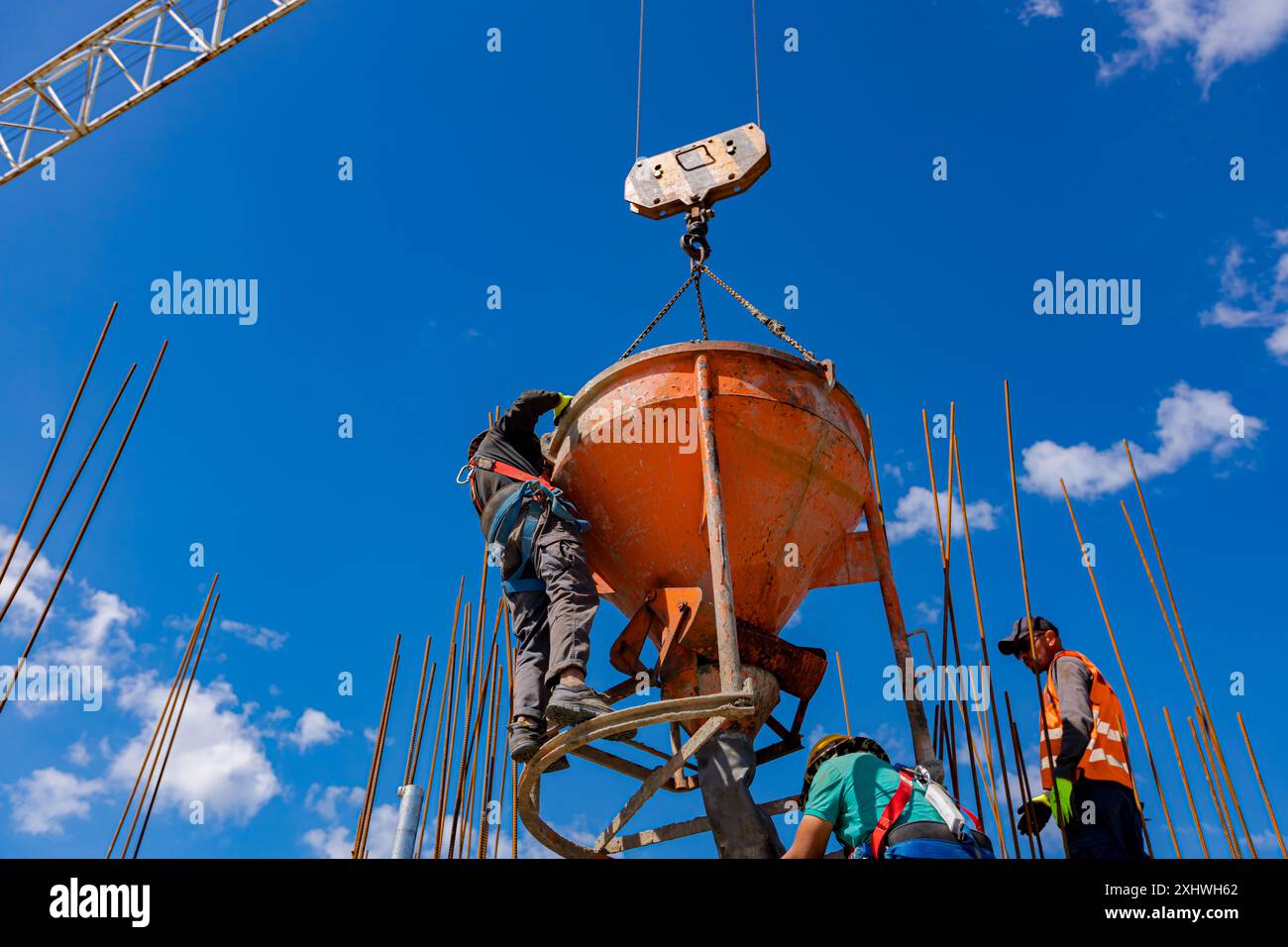 Construction workers are unloading conical metal bucket, transport and ...