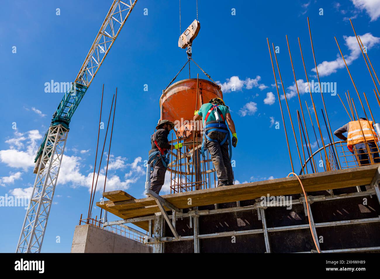 Construction workers are unloading conical metal bucket, pouring ...