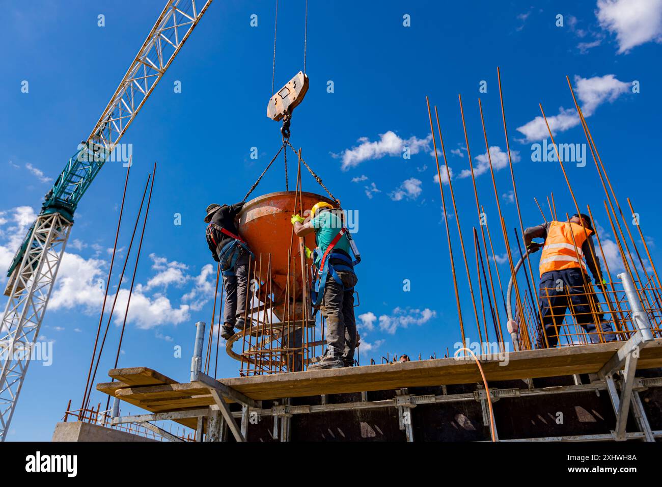 Construction workers are unloading conical metal bucket, pouring ...
