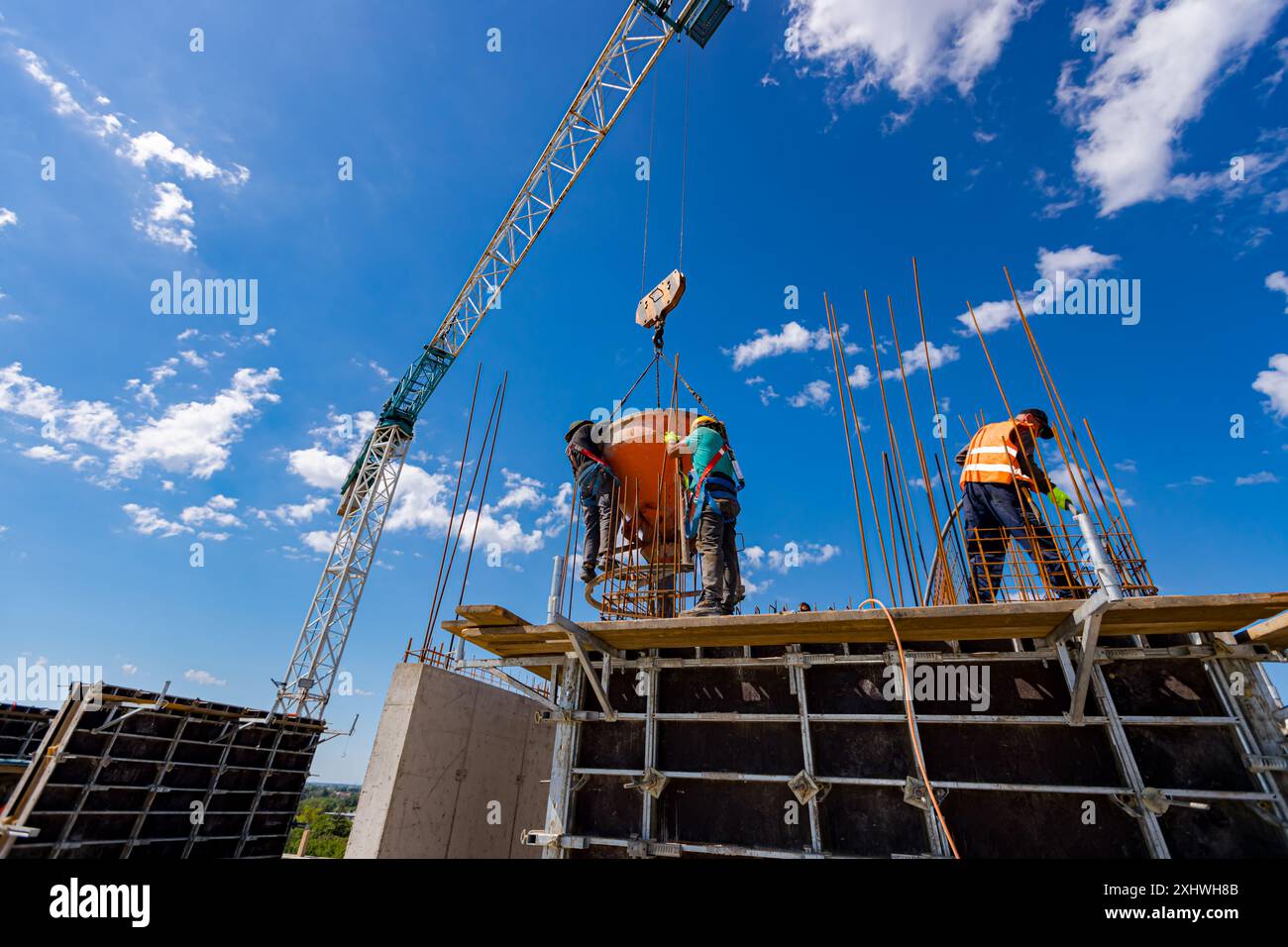 Construction workers are unloading conical metal bucket, pouring ...