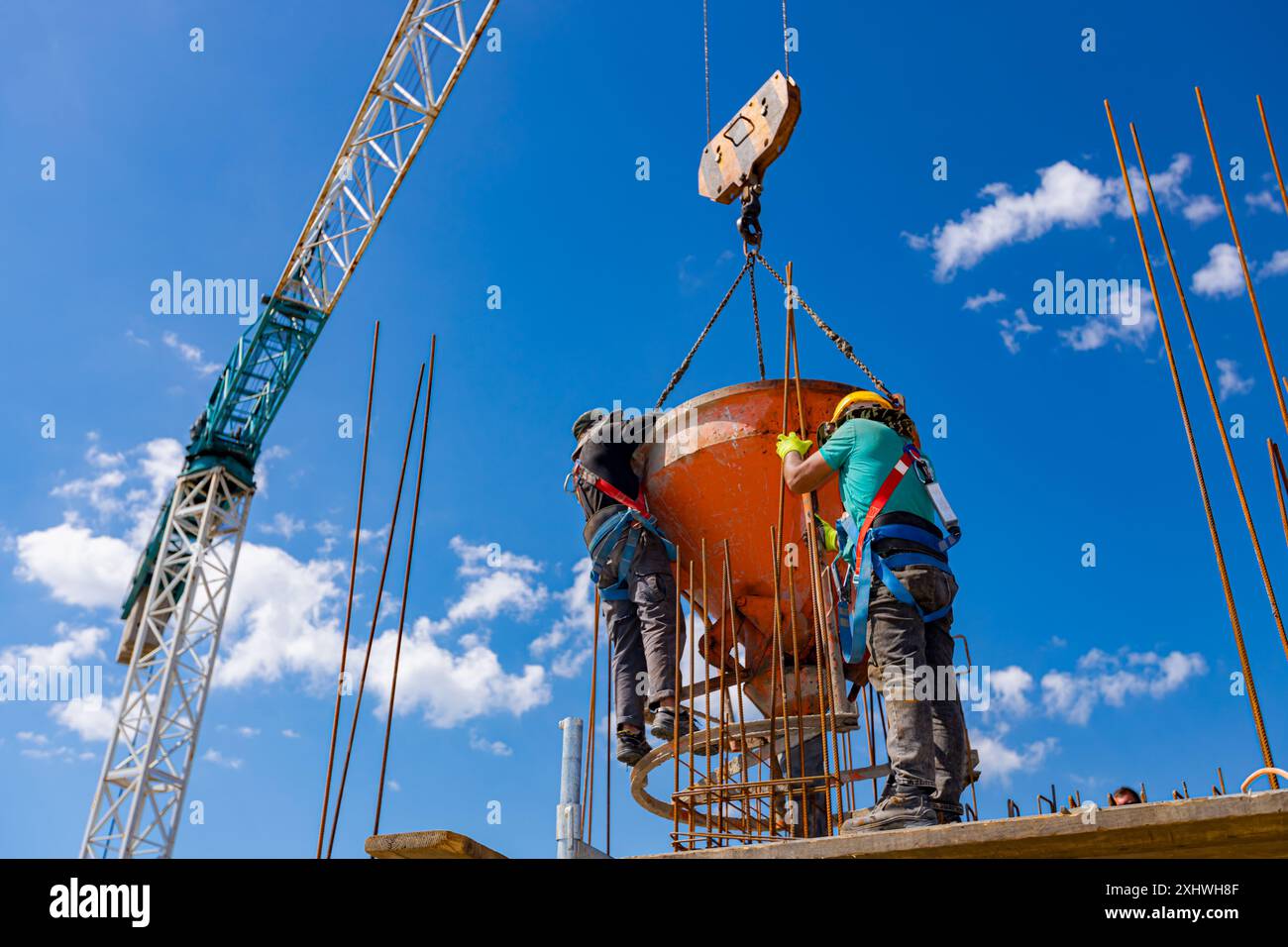Construction workers are unloading conical metal bucket, transport and ...