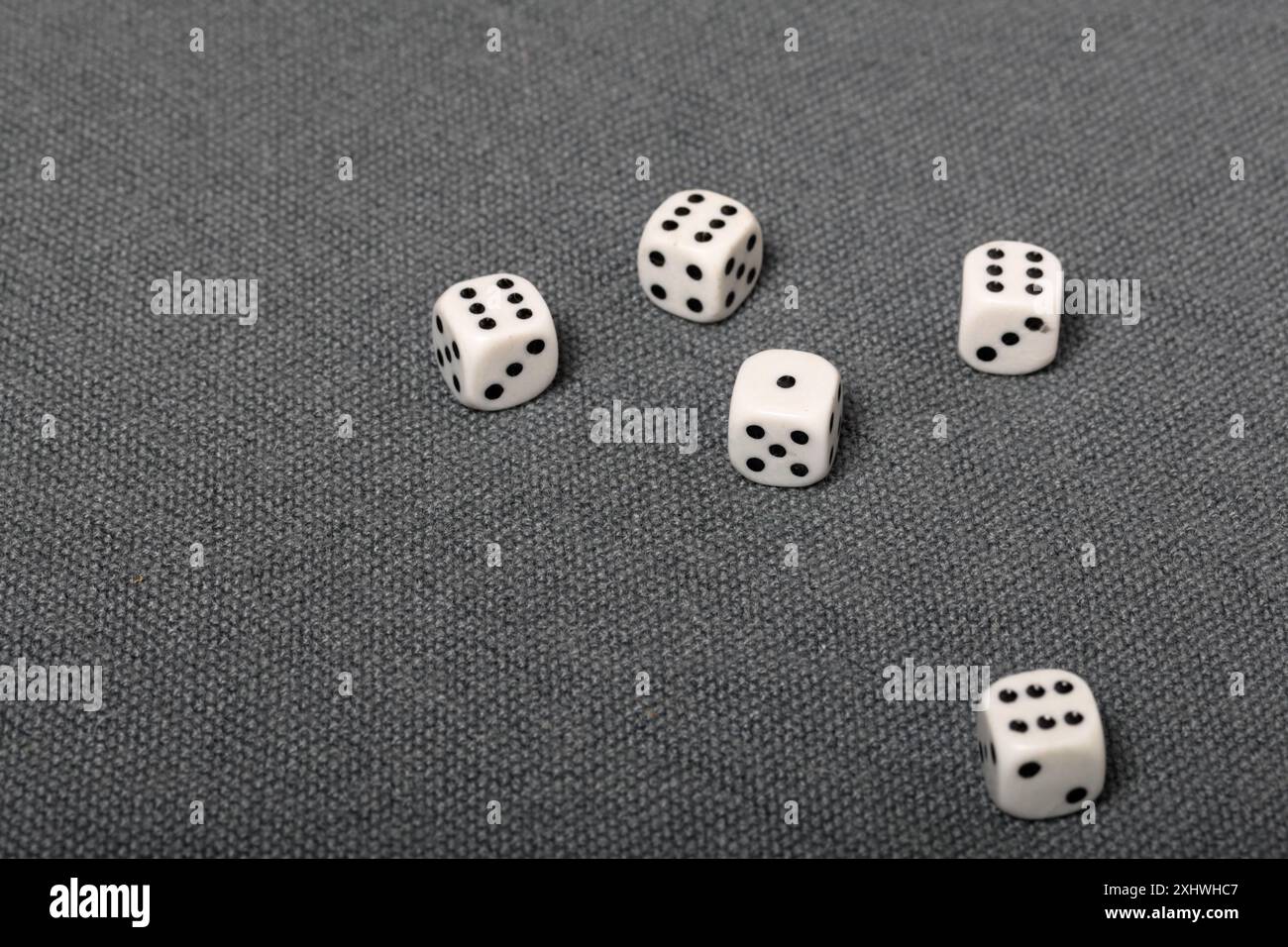 White dice with black markings. Lie on a surface covered with a coarse ...