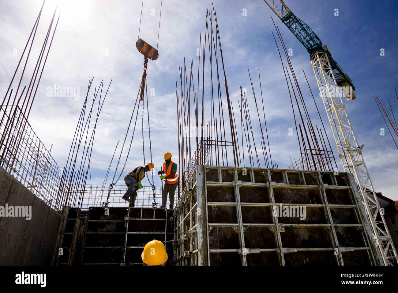 Tower crane helps construction workers, with safety vest and helmets ...