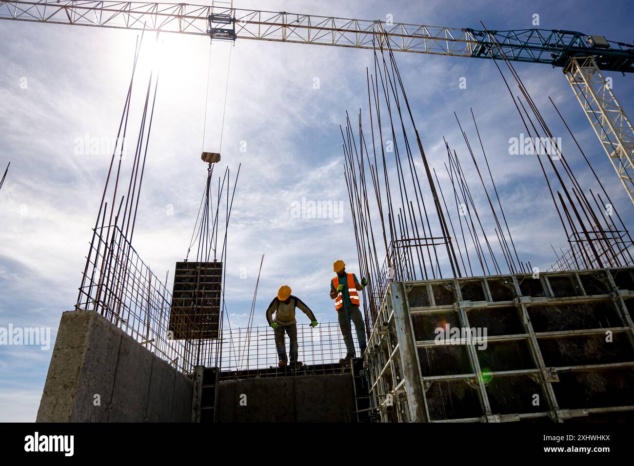 Tower crane helps construction workers, with safety vest and helmets ...