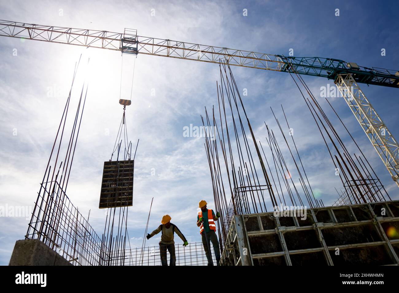 Tower crane helps construction workers, with safety vest and helmets ...