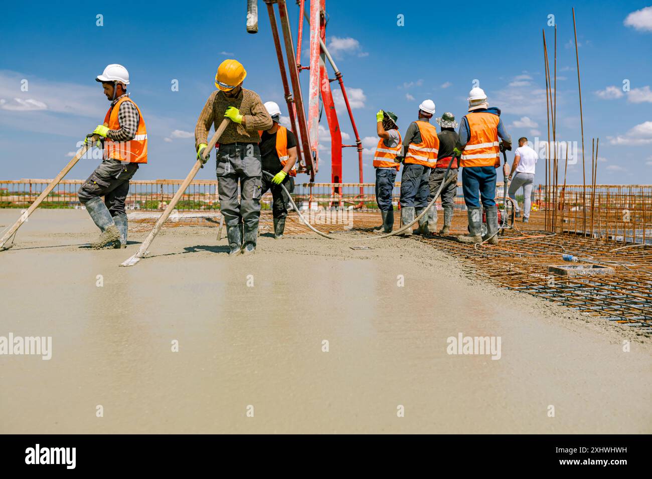 Team of construction workers are pouring and leveling fresh concrete ...