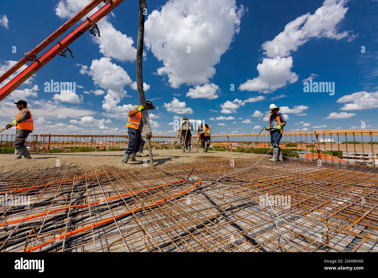Construction worker in rubber boots is directing pump tube on right ...