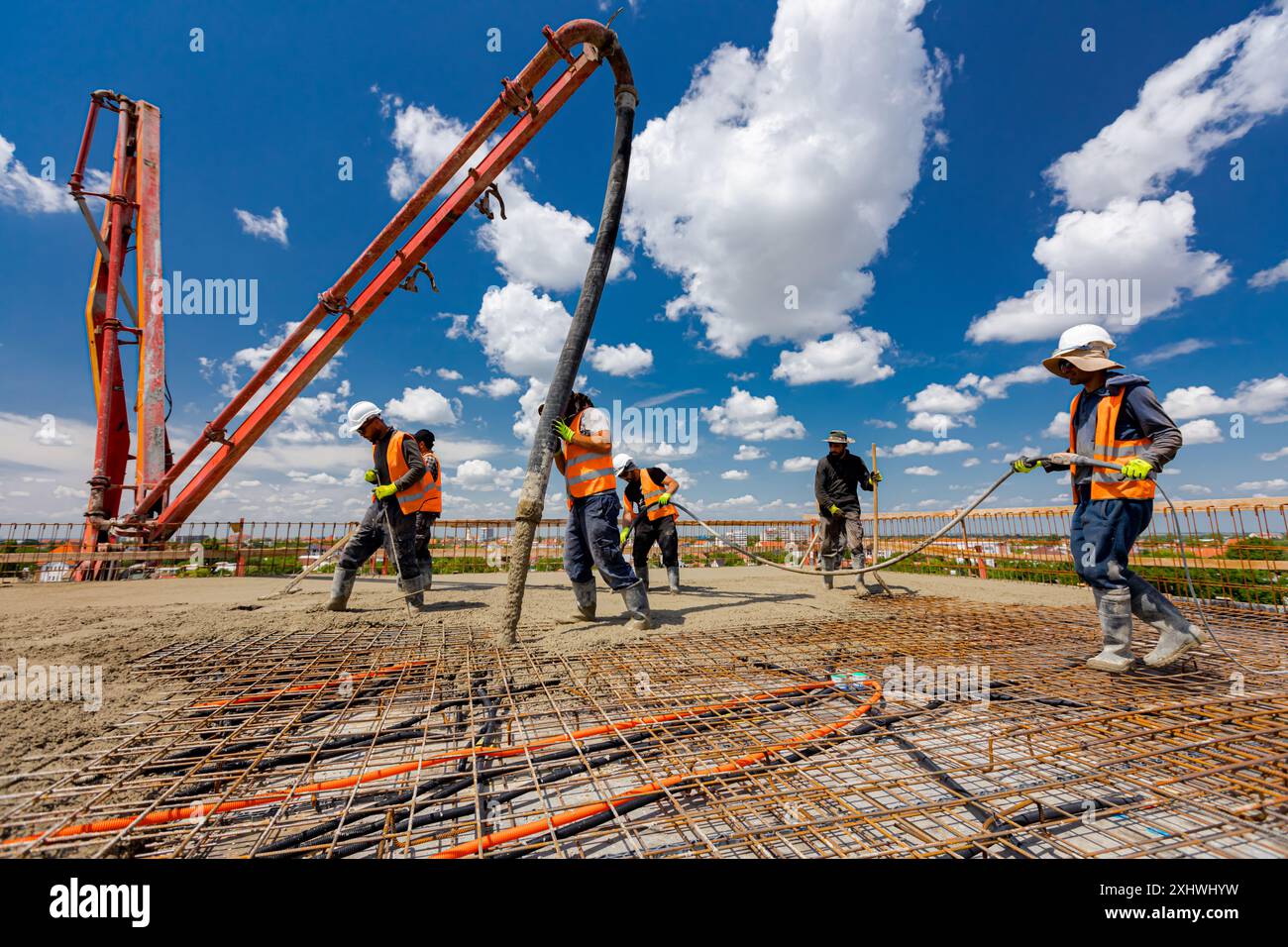 Construction worker in rubber boots is directing pump tube on right ...