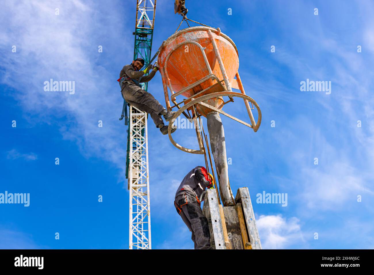 Construction workers are unloading conical metal bucket, transport and ...