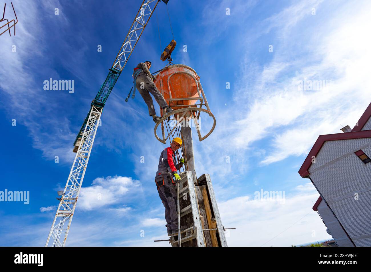 Construction workers are unloading conical metal bucket, pouring ...