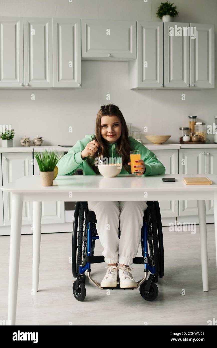 A young brunette woman in a wheelchair is eating breakfast at a kitchen ...