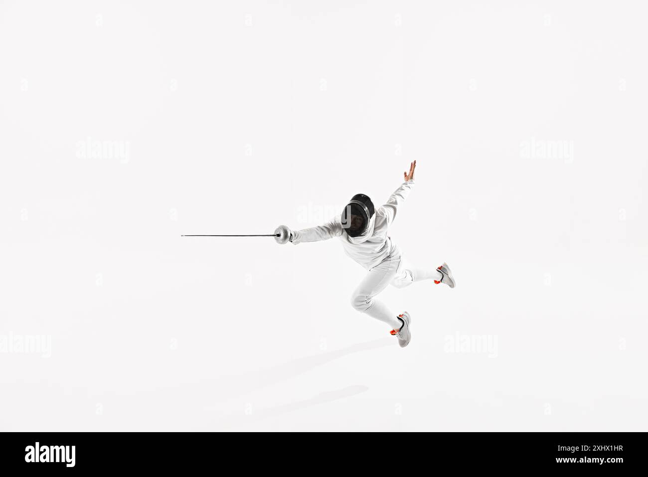 Fencer, outfitted in white suit and mask, strikes attacking pose with ...