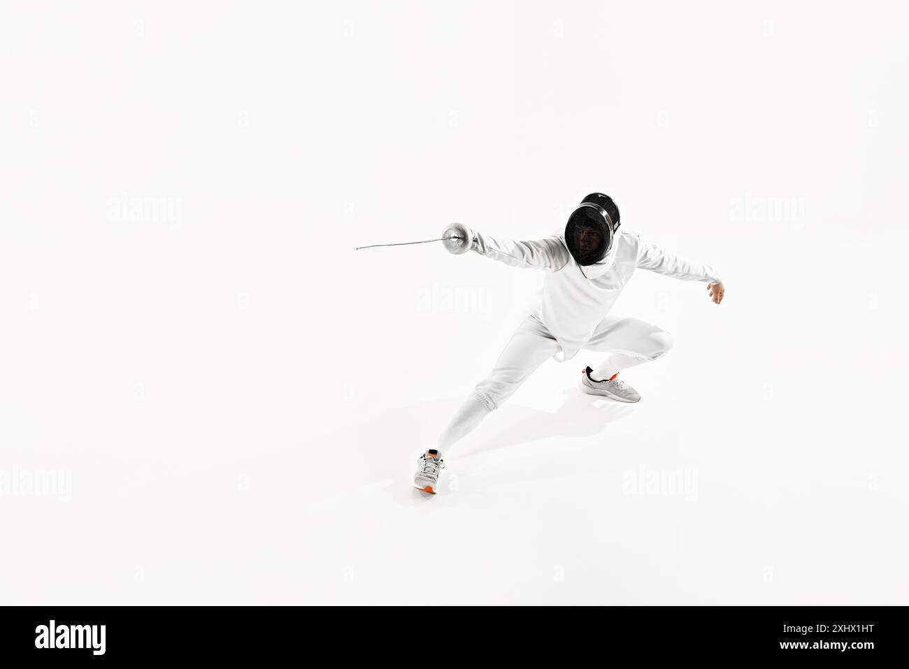 Young man, fencer, in full gear including mask, in attacking pose ...