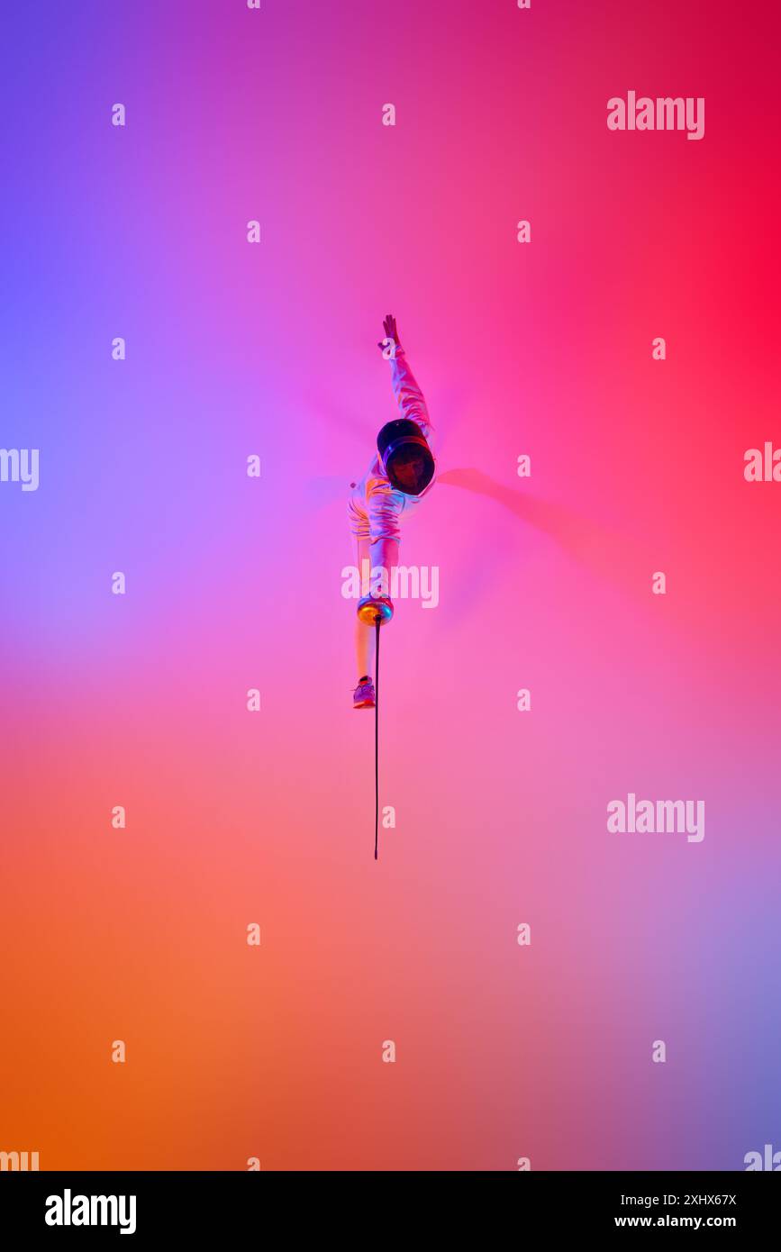 Fencer leaping in motion to attack opponent in mixed neon lights ...