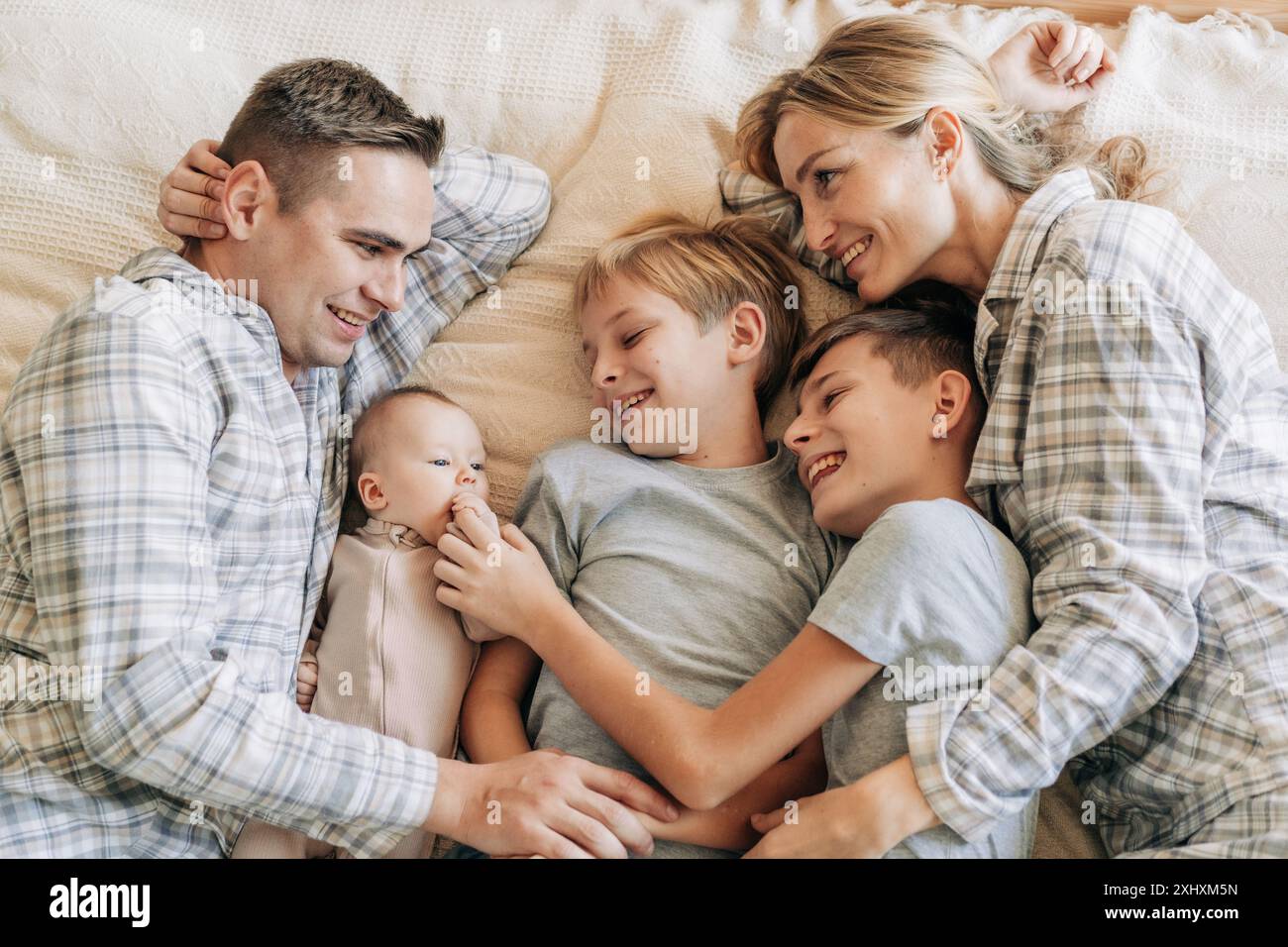 Parents and three children lie on the bed and bonding. Family happiness ...