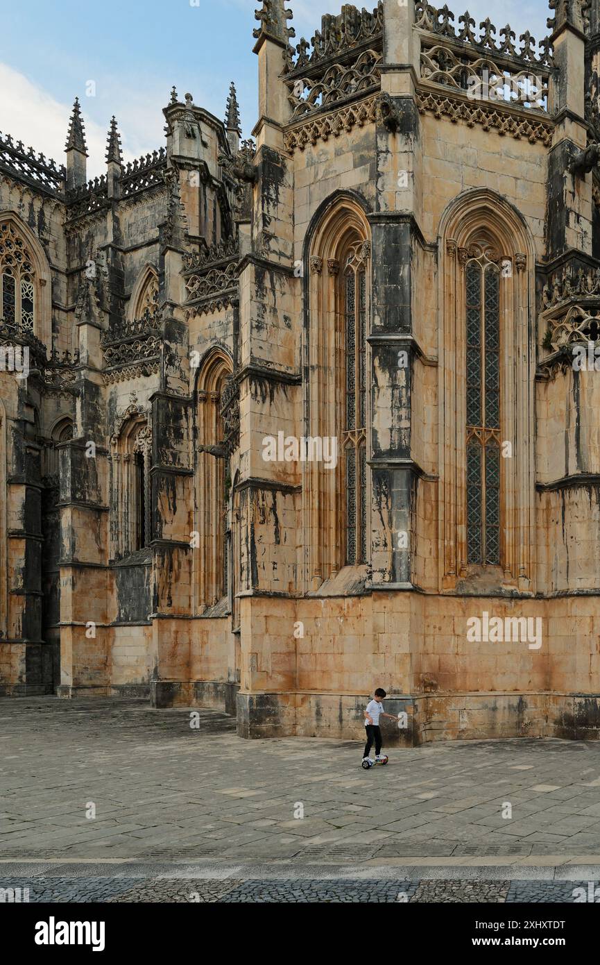 Child rides a self-balancing scooter past the gothic facade of batalha ...