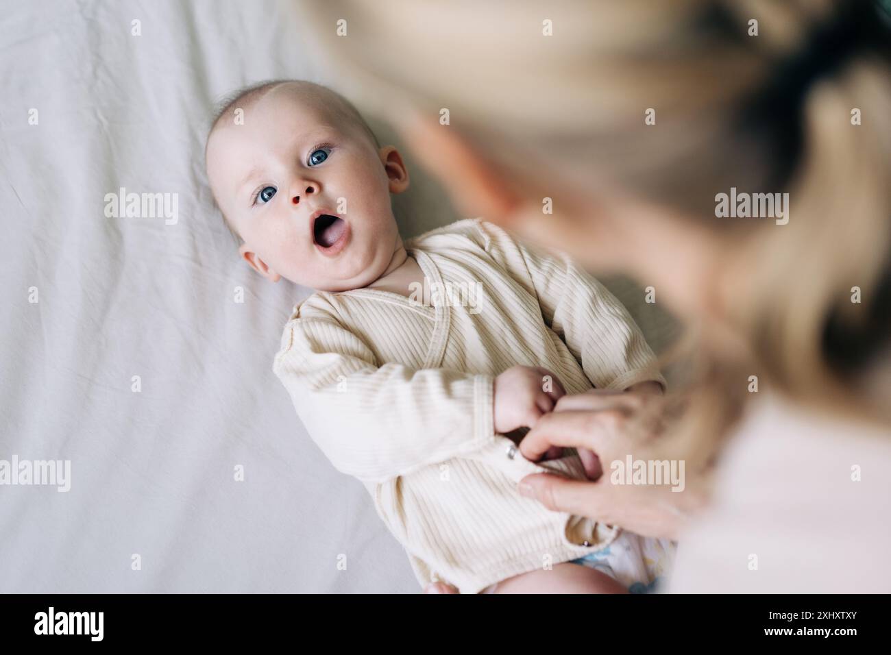 Mom changes the bodysuit of a cheerful cute baby after changing the ...
