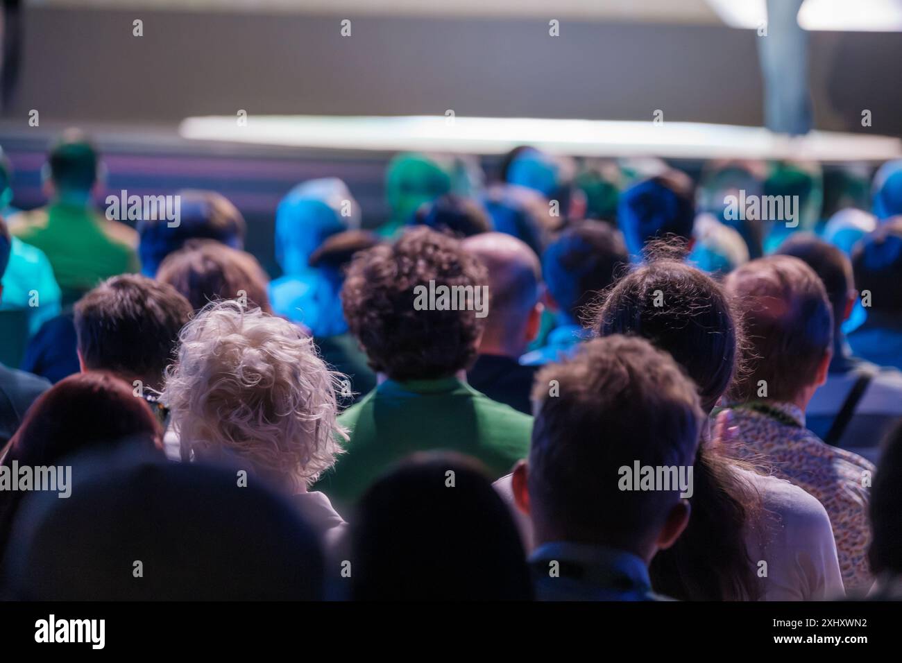 Rear view of a diverse audience attending a conference or seminar in a ...
