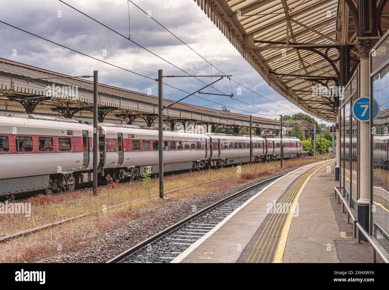 A train stands at a railway station platform close to a 19th Century ...
