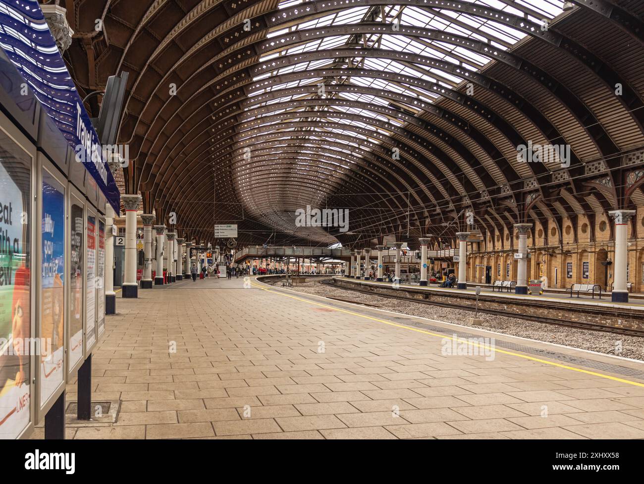 A railway station platform, lined by columns, curves into the distance. A historic 19th Century ...