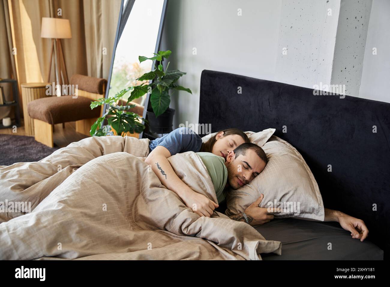 A young gay couple snuggles together in bed, showcasing intimacy and ...