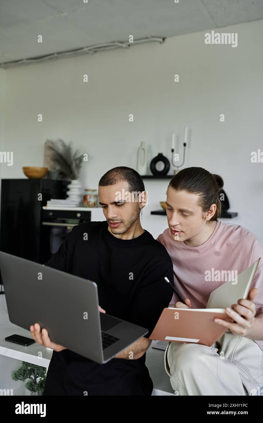 A young gay couple is working together on a laptop in a modern home ...