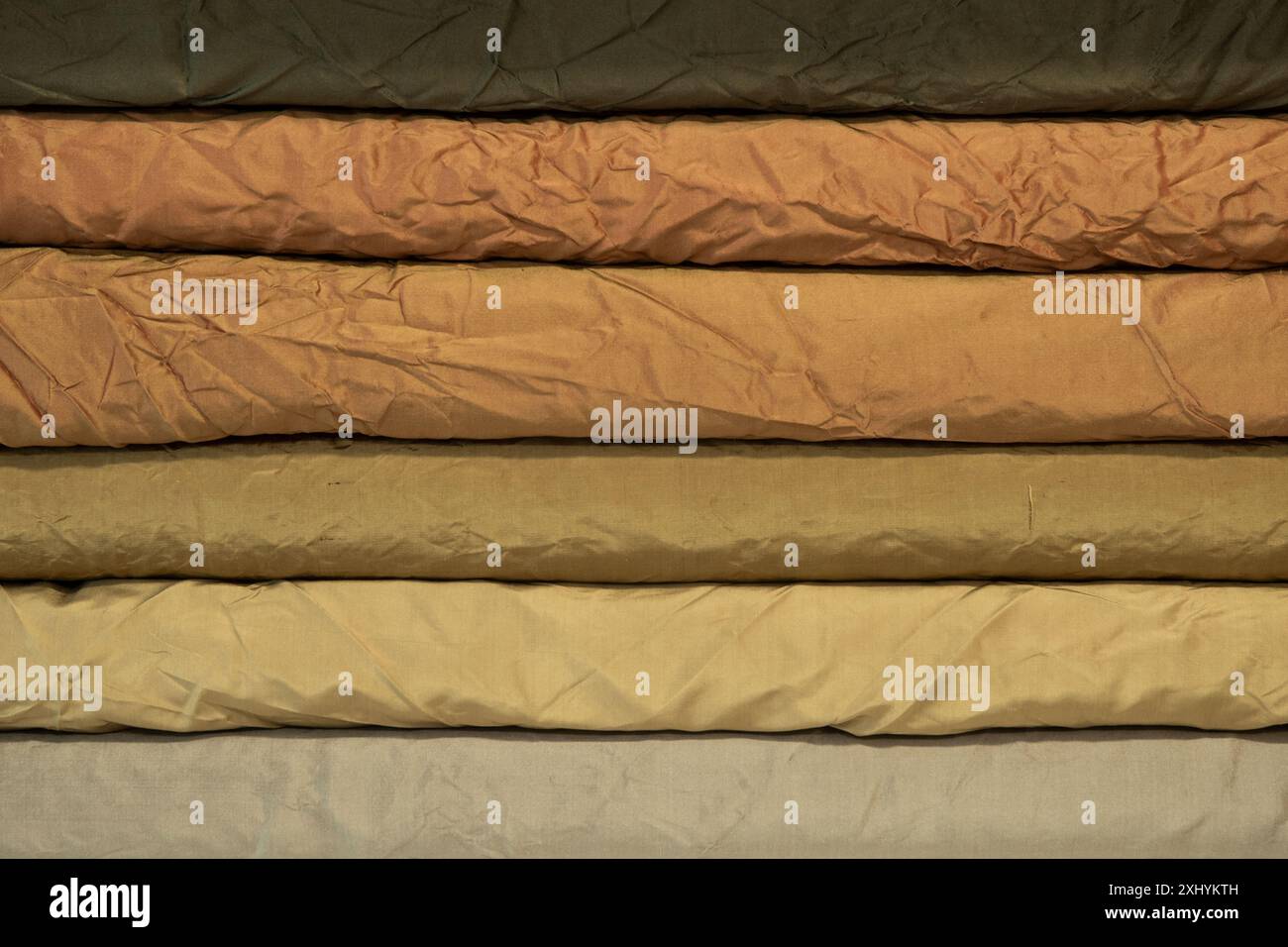 Different color shades of folded silk fabric on shelf closeup as ...