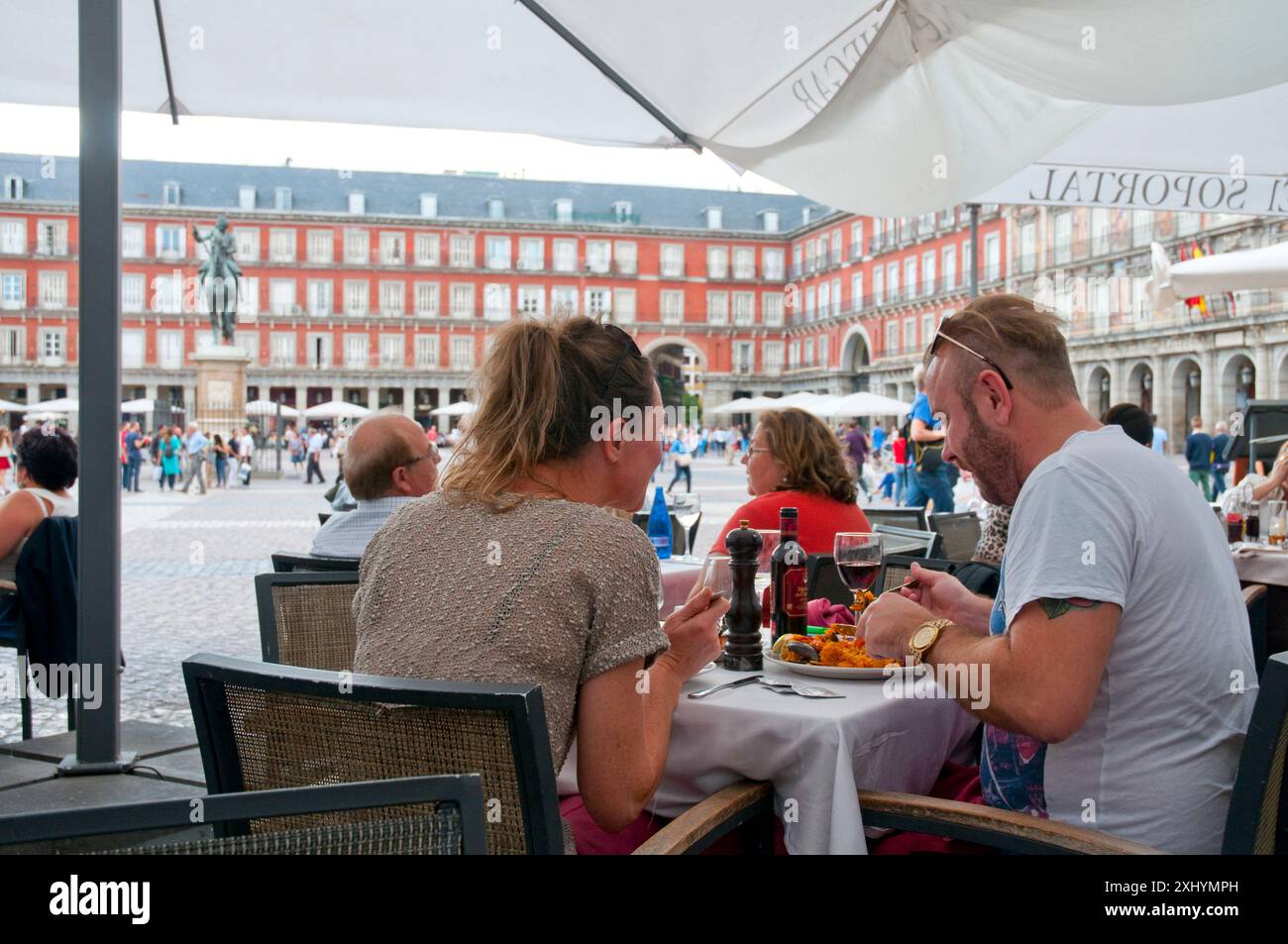Couple of tourists eating paella in a terrace. Main Square, Madrid ...