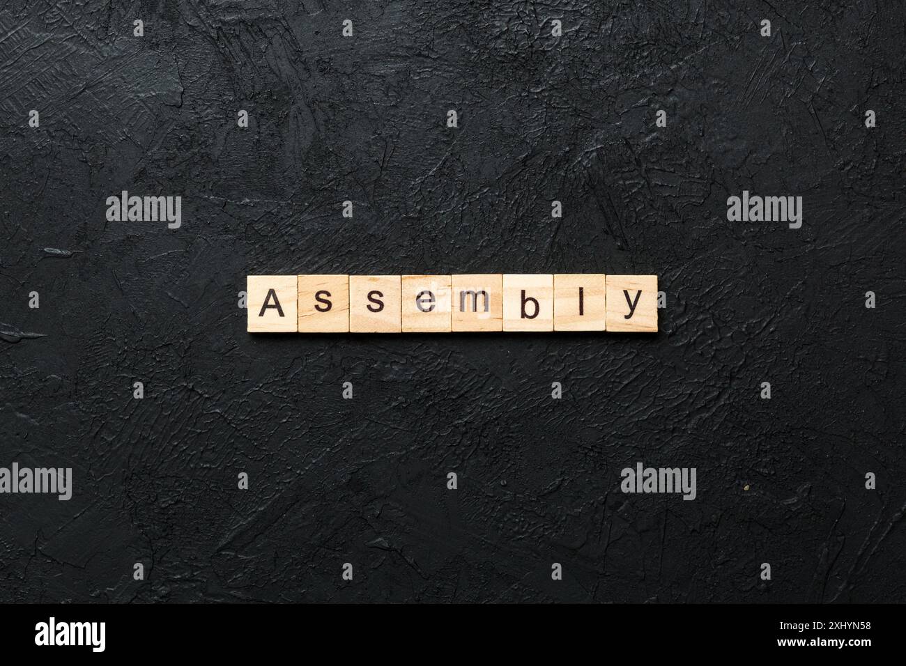 ASSEMBLY word written on wood block. ASSEMBLY text on cement table for ...