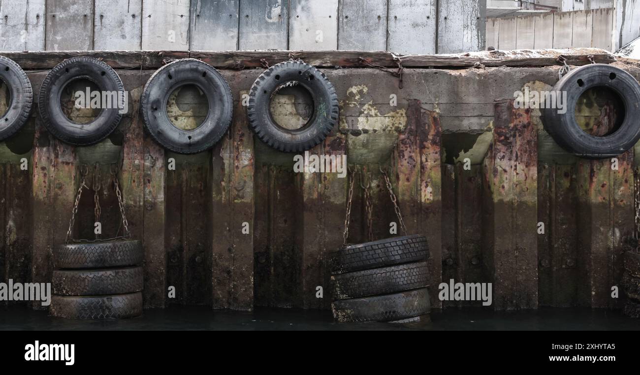 Mooring wall with rubber bumpers made of old used car tyres. Close up ...