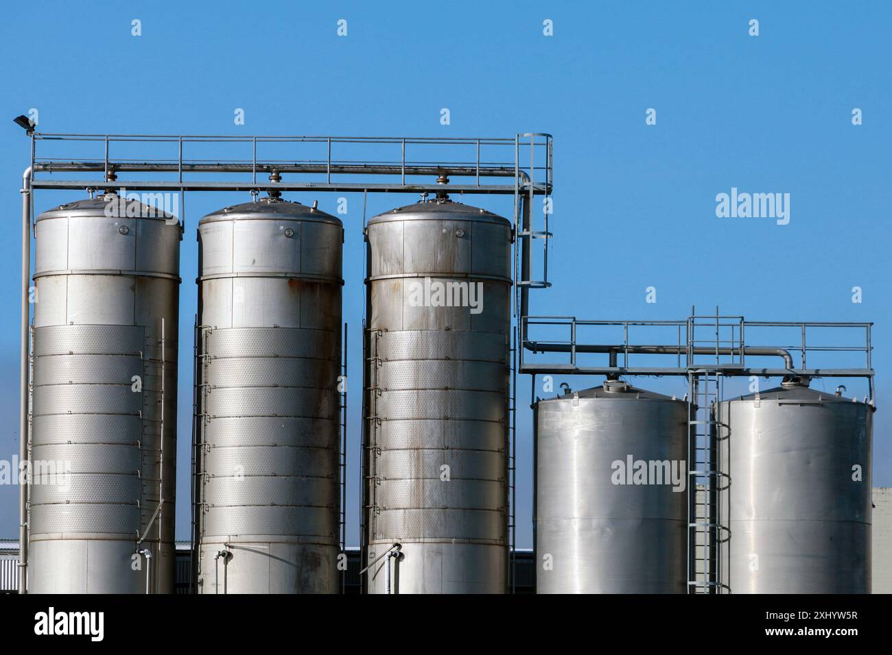 Abstract industrial background photo, shiny metal tanks placed in a row ...