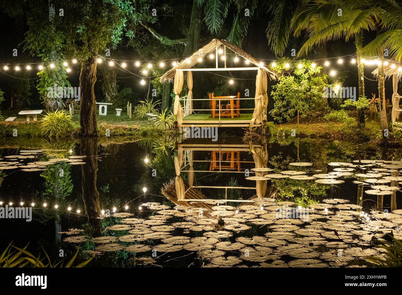 Pergola with glowing lights by the water. Gazebo with lights by the ...