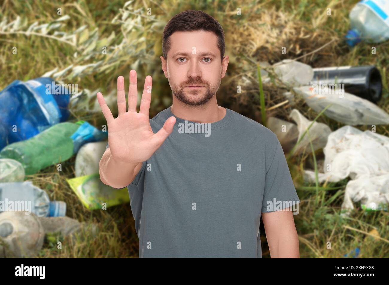 Environmental pollution. Man showing stop gesture among garbage on ...