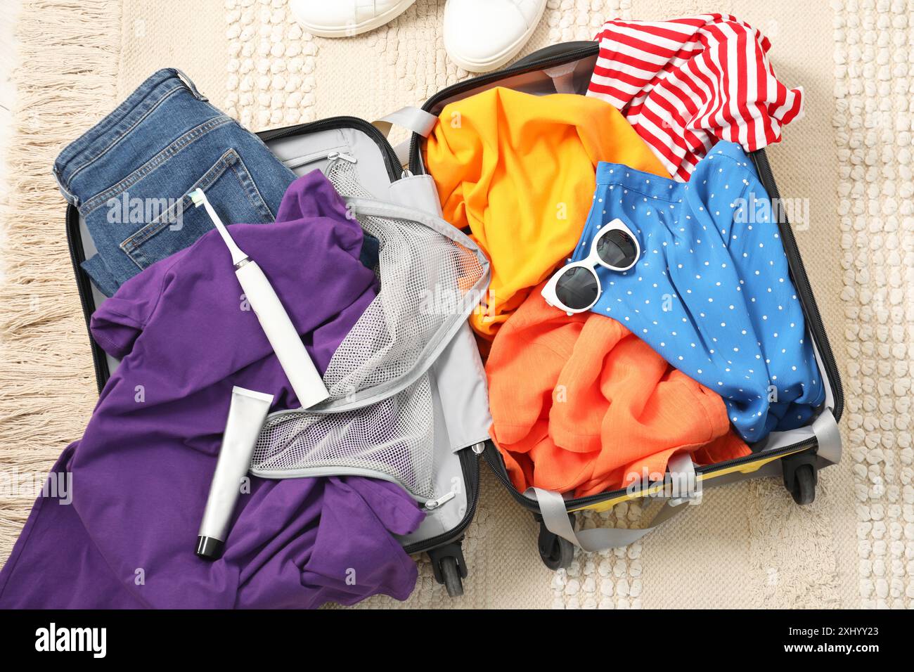 Open suitcase with traveler's belongings on floor, flat lay Stock Photo ...