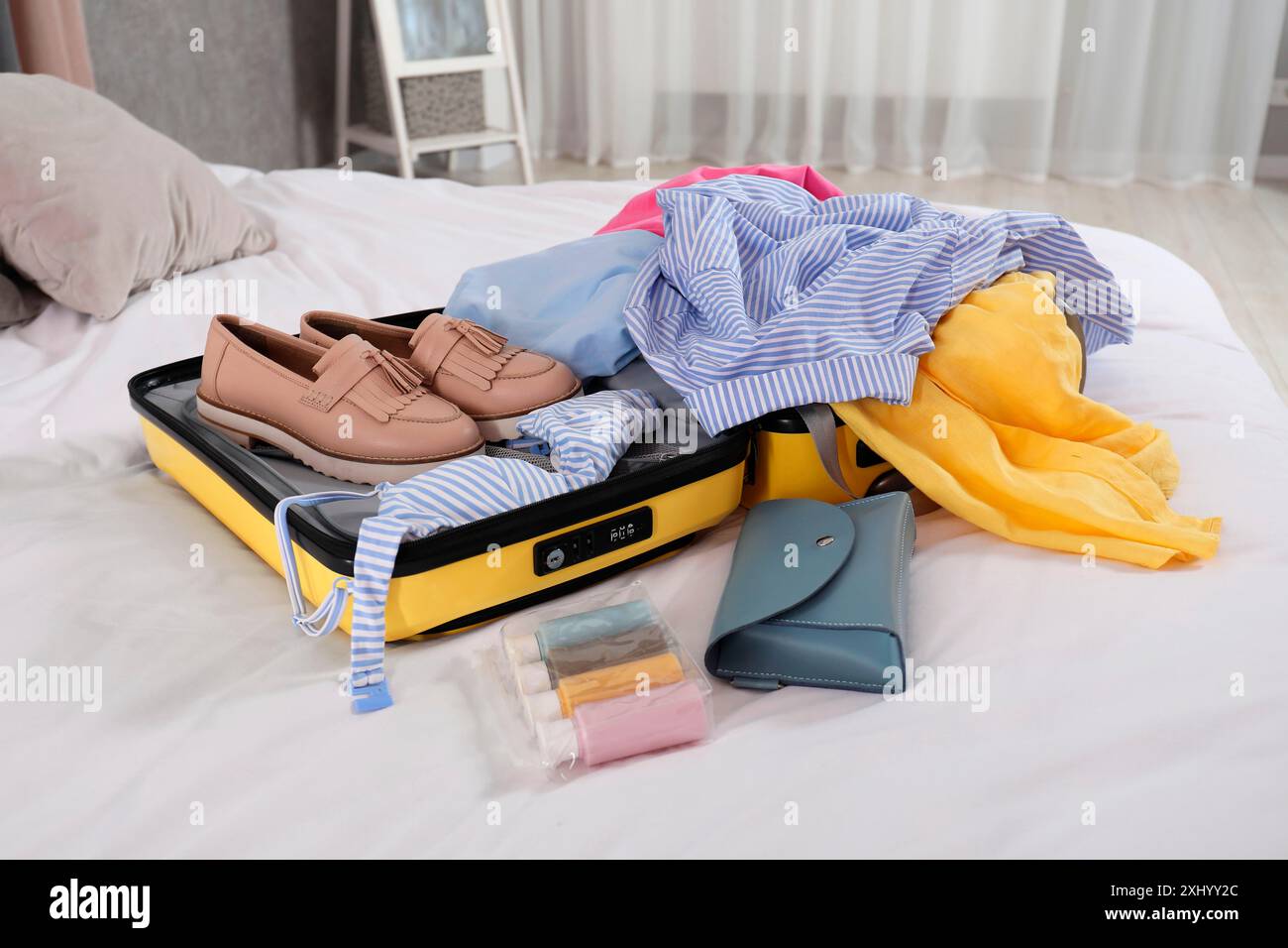 Open suitcase with traveler's belongings on bed Stock Photo - Alamy