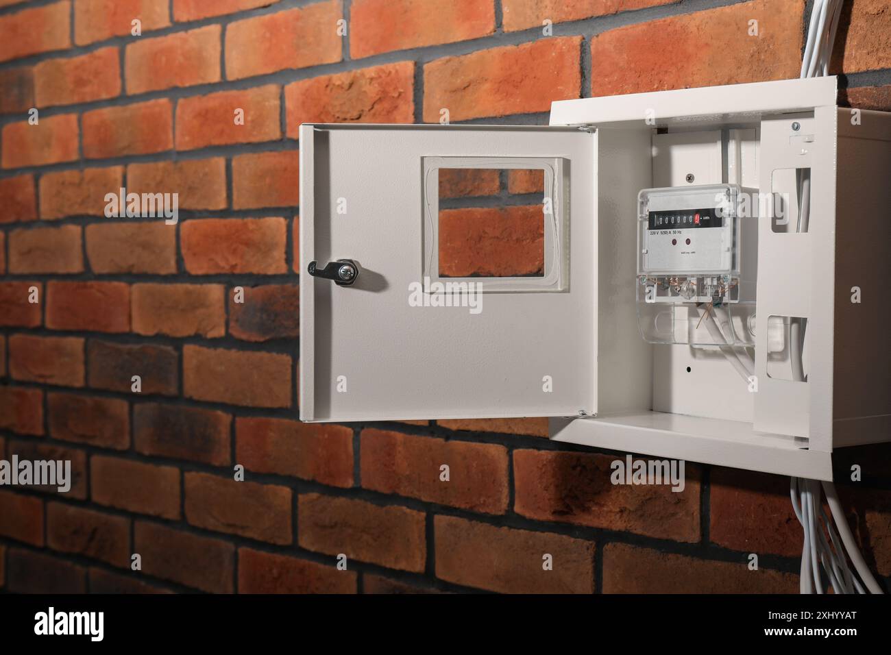 Electric meter in fuse box on red brick wall. Energy measuring device ...