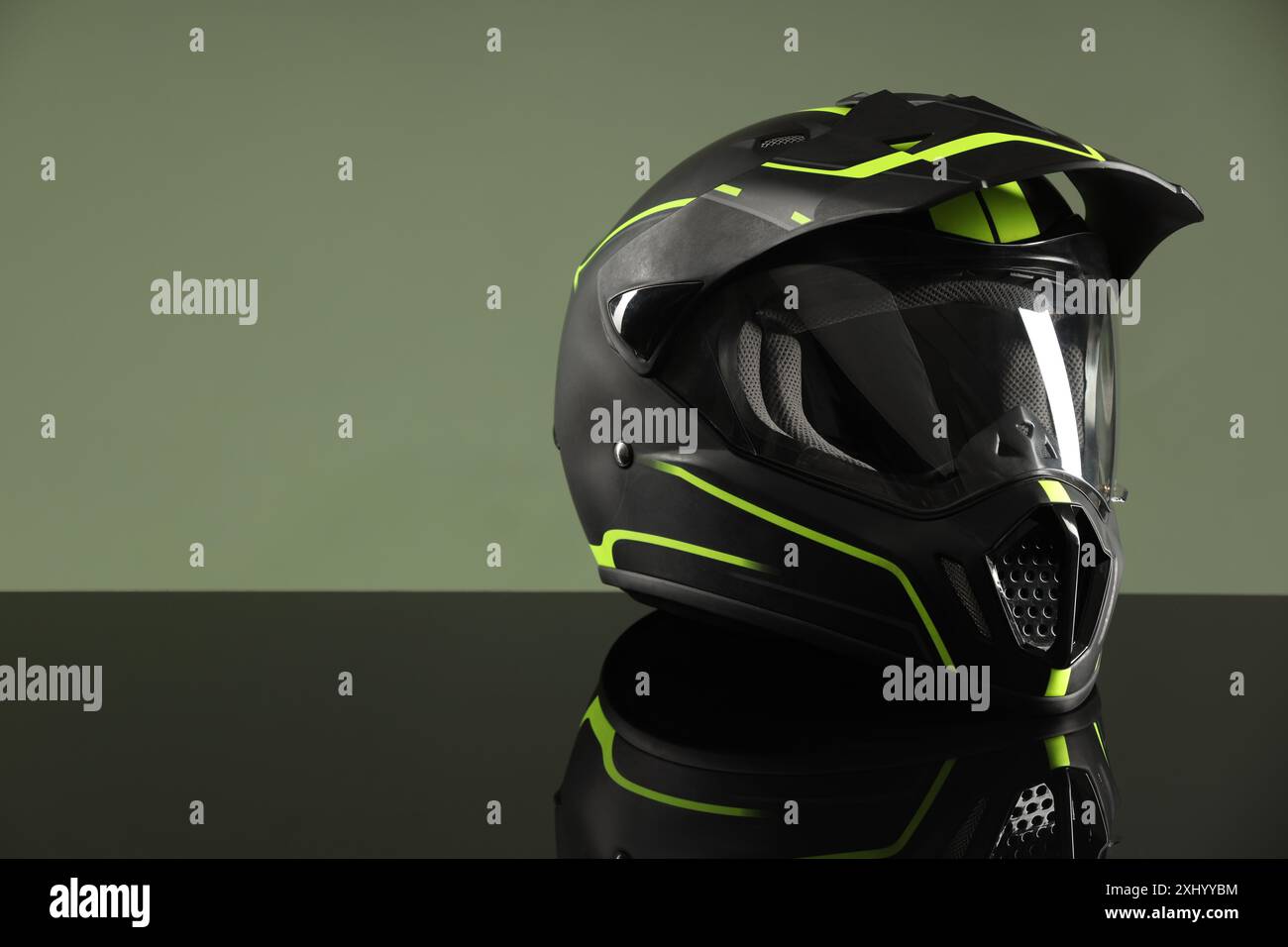 Modern motorcycle helmet with visor on mirror surface against light ...
