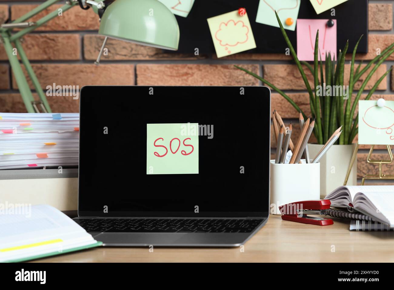 Sticky note with word SOS, laptop and stationery on wooden table at ...