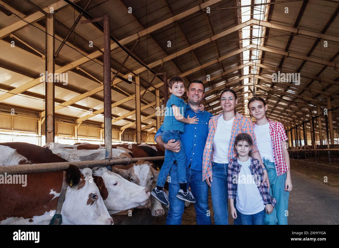 A happy family of farmers in a cowshed. A young married couple and ...