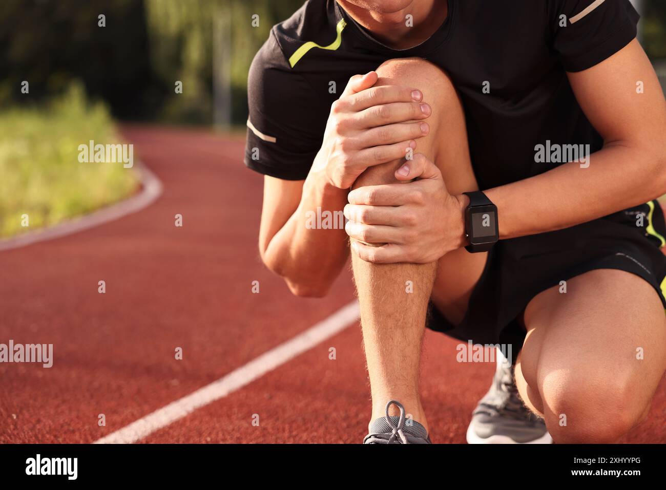 Sportsman with leg injury suffering from knee pain at stadium, closeup ...