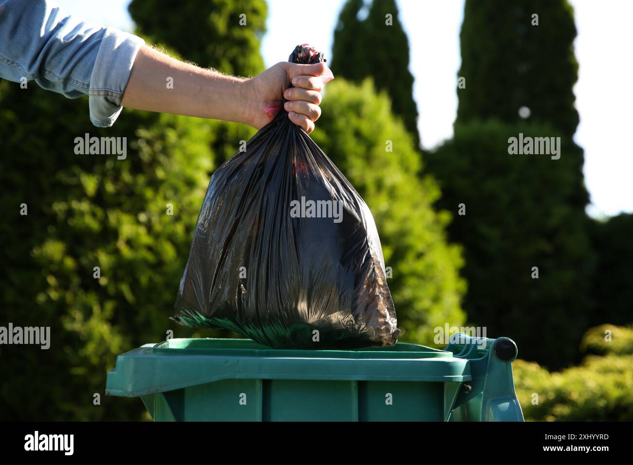 Man throwing trash bag into bin outdoors, closeup Stock Photo - Alamy