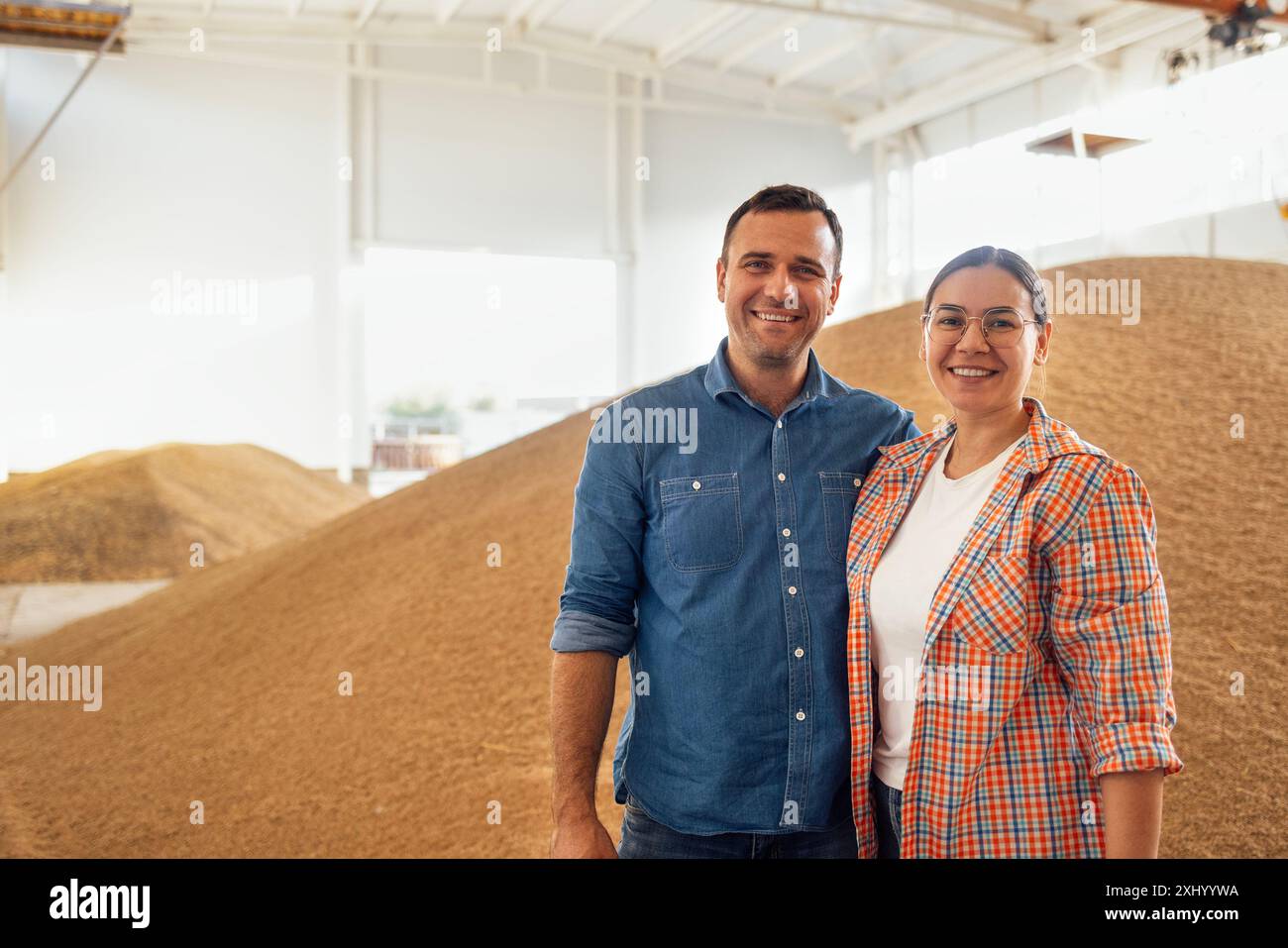 A young married couple are smiling in a grain barn. A charming woman ...
