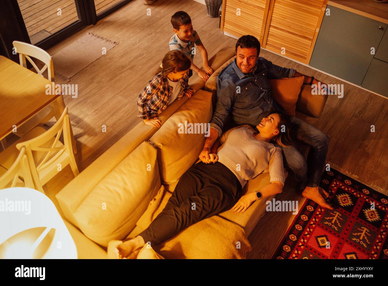 A young married couple with children is relaxing in the living room. A ...