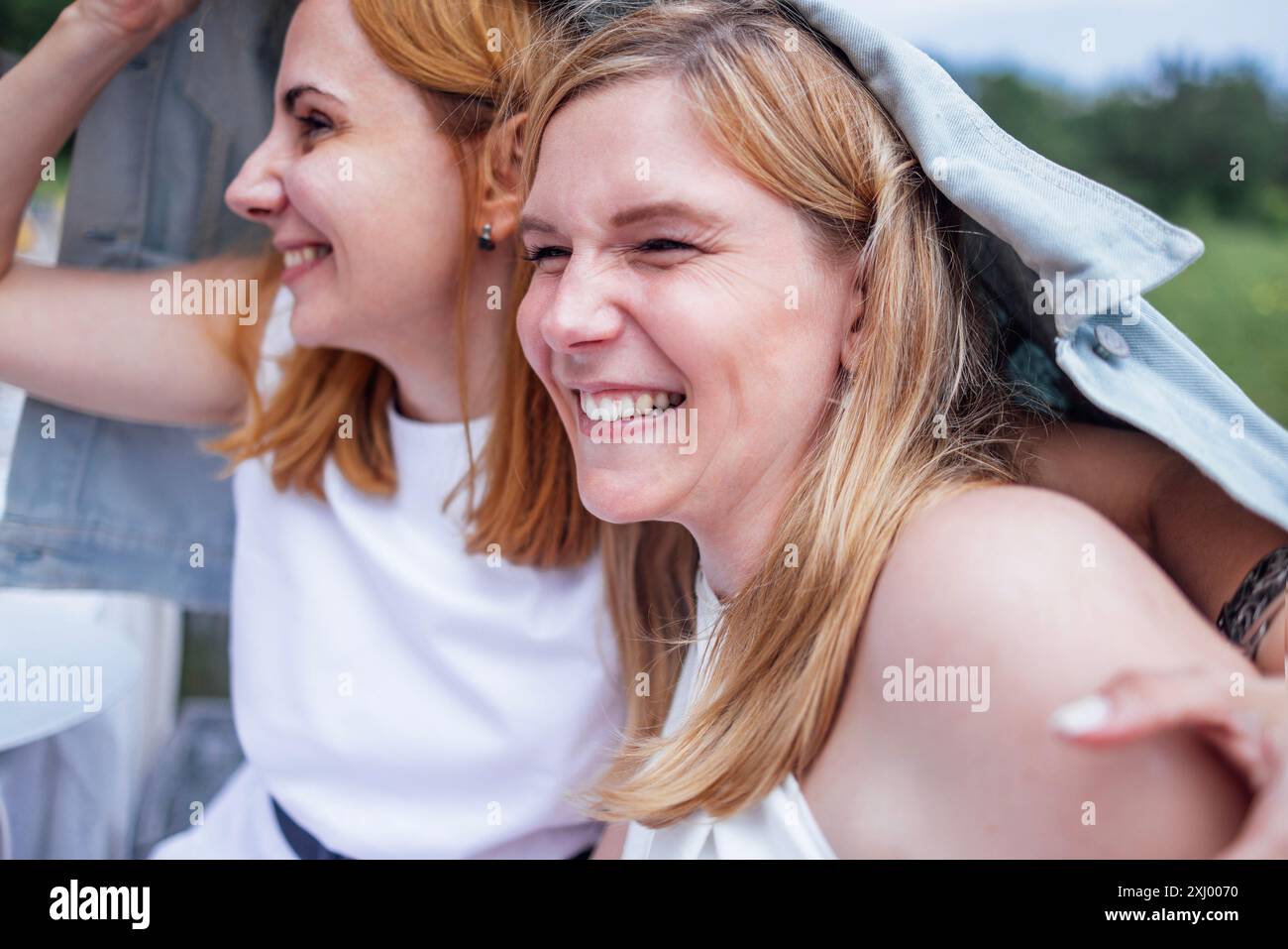 Two young women in white clothes laugh and cover themselves with a ...
